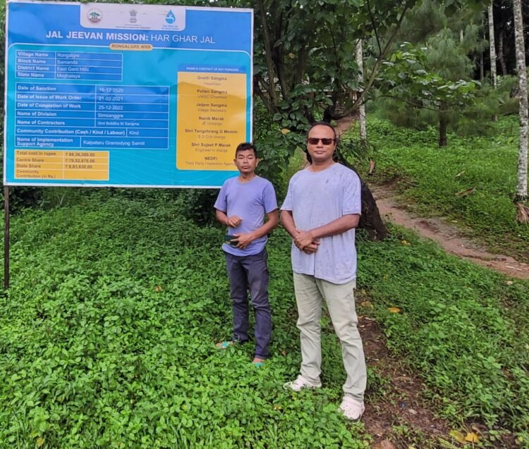 Bernard Marak (right) next to a JJM completion signboard | Highland Post